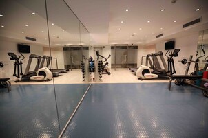 Uma academia com equipamentos de ginástica, um espelho na parede e piso azul.