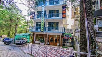 Um edifício com vários andares, fachada verde e branca, um bar e um restaurante chamado 'Greenwoods Inn'.