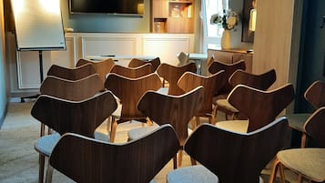 Uma sala de conferências com cadeiras de madeira e uma grande televisão de tela plana.