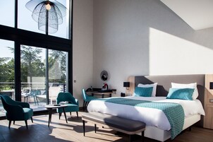 Quarto de hotel moderno com uma cama grande, uma escrivaninha e cadeiras.