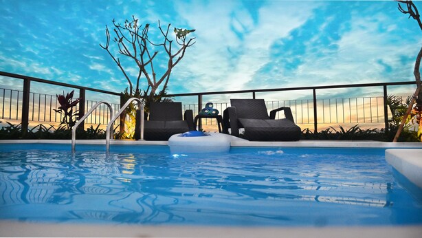 Área de piscina com espreguiçadeiras e vista do céu.
