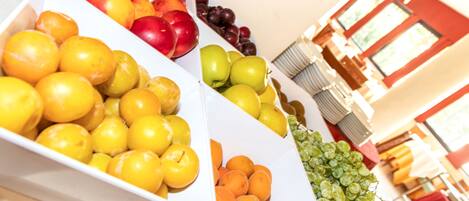 Exposição de frutas com diferentes tipos de maçãs, uvas e laranjas.