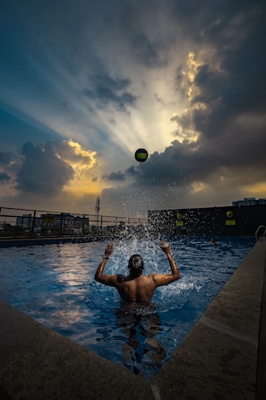 Uma pessoa brincando com uma bola em uma piscina.