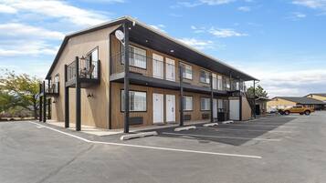 Um hotel com vários andares, design moderno, com varandas, estacionamento e céu claro.