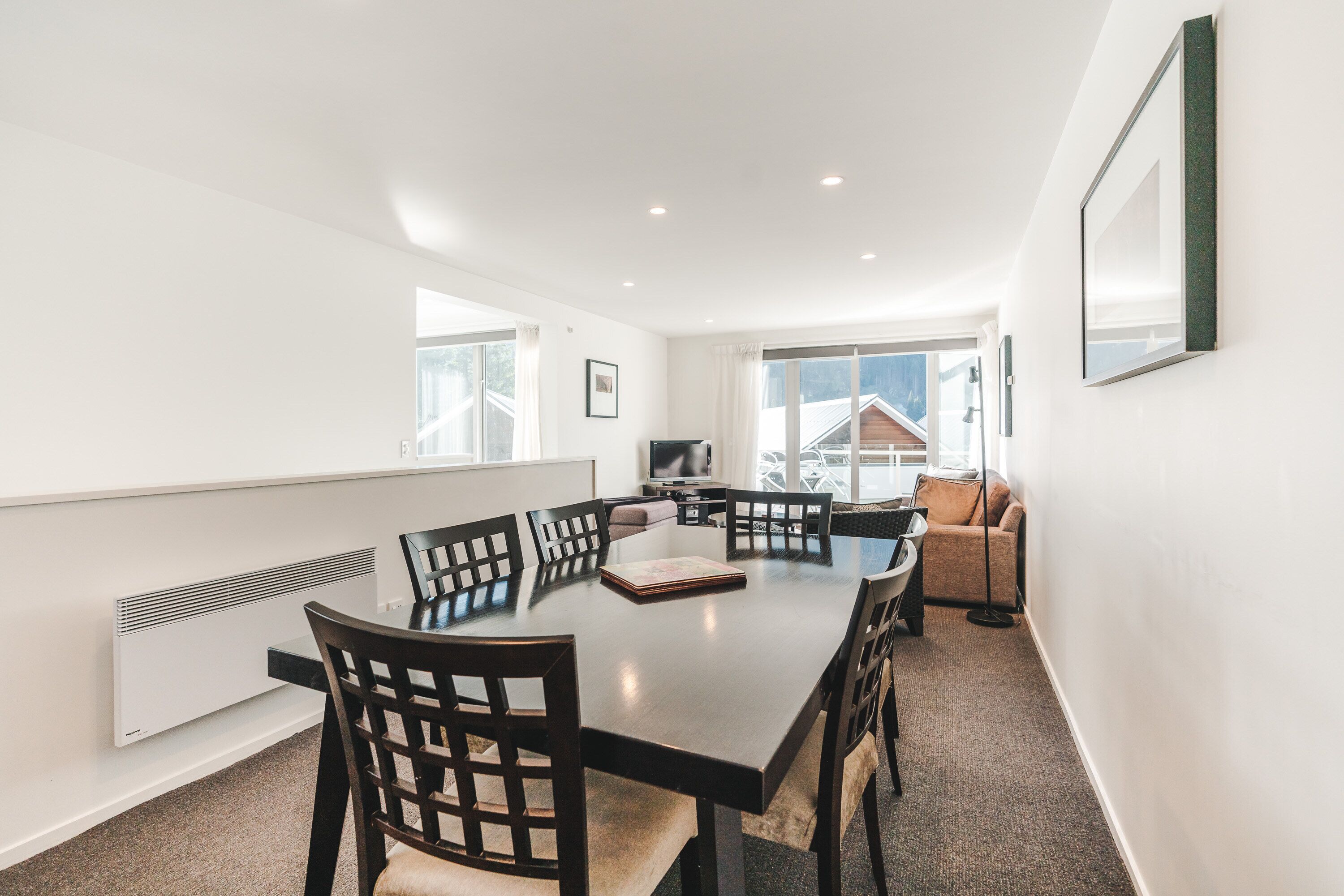Uma sala de jantar moderna com uma mesa retangular, seis cadeiras e um ar condicionado embutido.