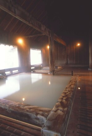 Uma área de spa com hidromassagem, vigas de madeira e uma parede de pedra.