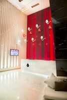 Um lobby moderno com uma parede de destaque vermelha, um sofá branco e uma TV de tela plana.