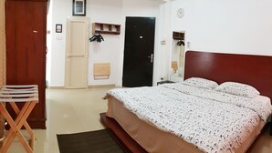 Quarto com uma cama, uma cadeira, um guarda-roupa, uma porta e uma pequena estante.