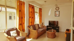 Uma sala de estar com móveis de vime, uma televisão e um relógio na parede.