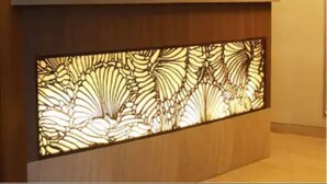 Uma receção com um painel de vitrais decorativo, relógios na parede e uma câmara de segurança.