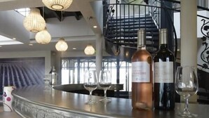 Uma área de bar com balcão curvo, garrafas de vinho e copos.