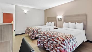 Quarto de hotel com duas camas, uma escrivaninha e uma cadeira.