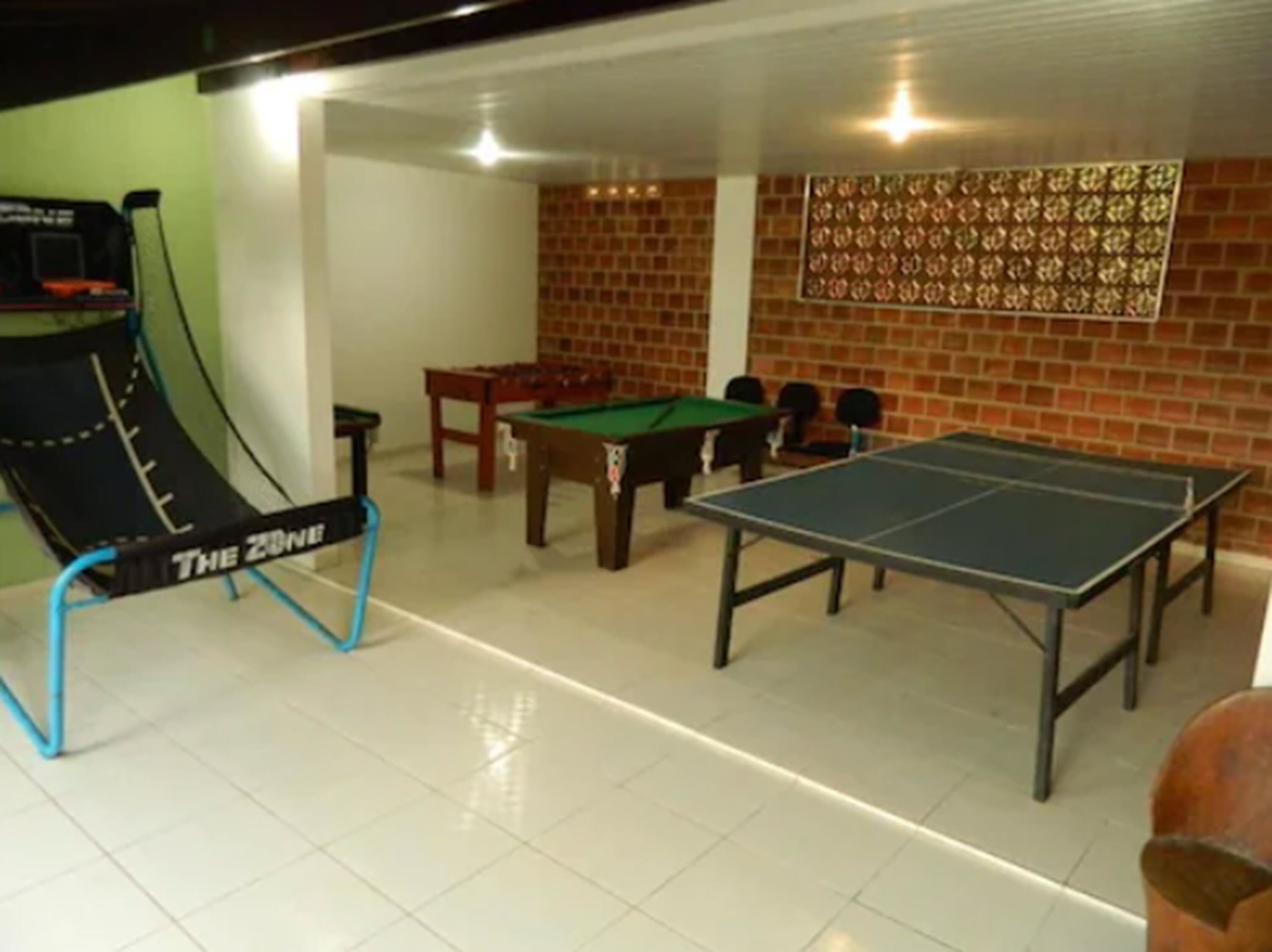 Um quarto com mesa de pingue-pongue, mesa de futebol de mesa e mesa de bilhar.