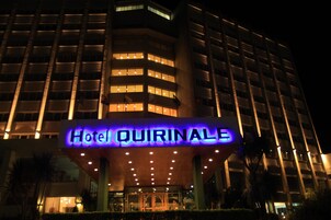 Edifício de hotel com uma placa iluminada de destaque que diz 'Hotel Quirinale'.