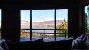 Quarto com uma grande janela com vista para um lago e montanhas.