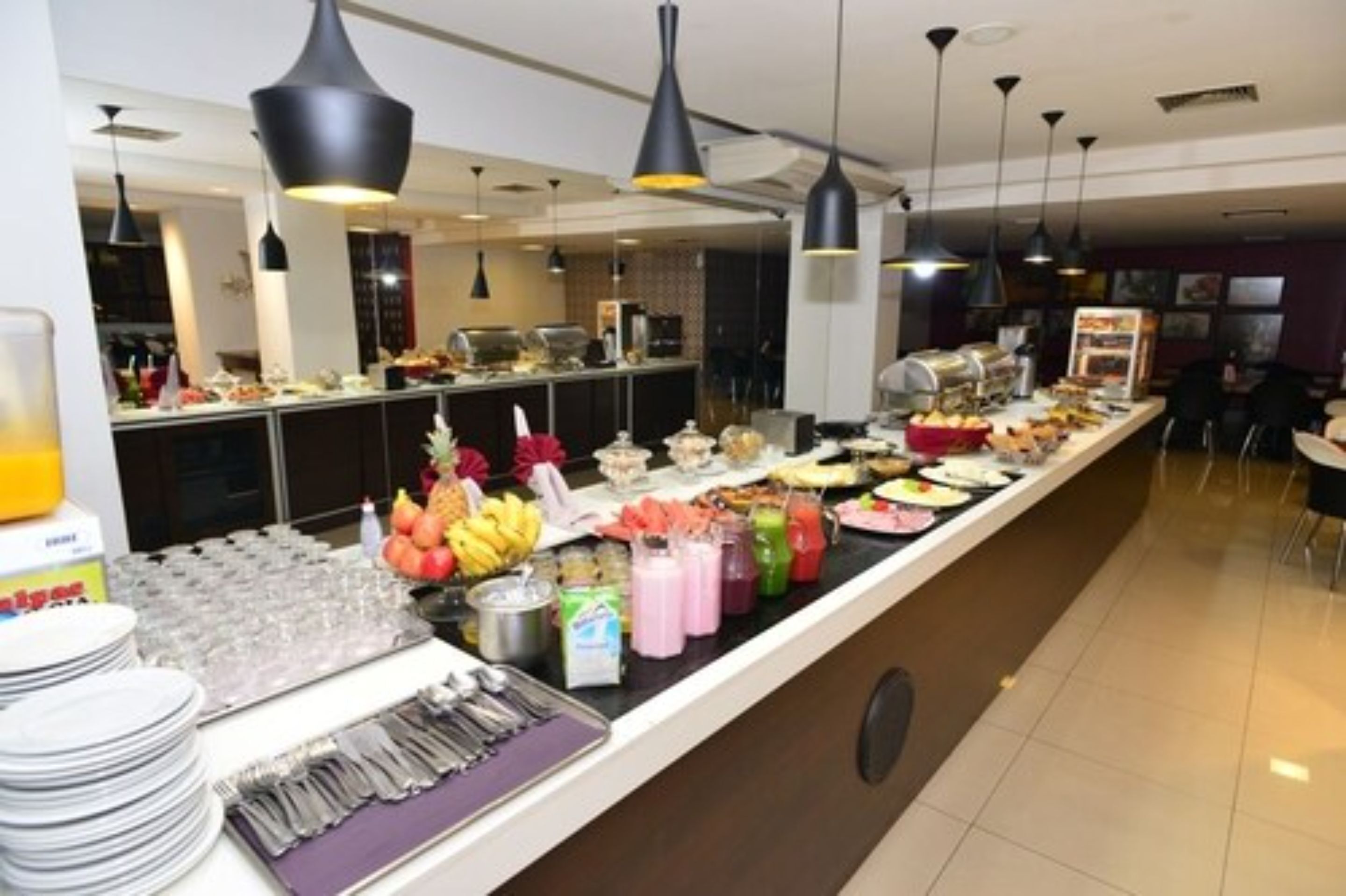Uma mesa de buffet com diversos alimentos, bebidas e utensílios.
