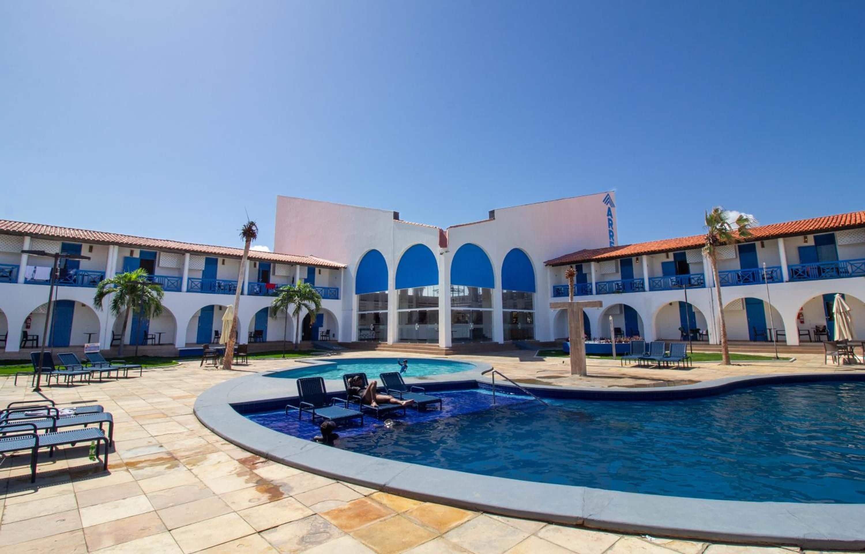 Hotel com piscina, área de estar ao ar livre e céu azul.