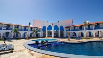 Hotel com piscina, área de estar ao ar livre e céu azul.