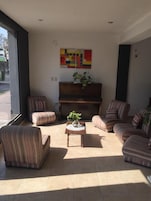 Uma sala de estar com sofás listrados, um piano e um quadro abstrato e colorido na parede.