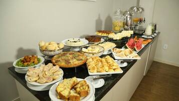 Mesa de buffet com diversos tipos de comida e um espaço para bebidas.