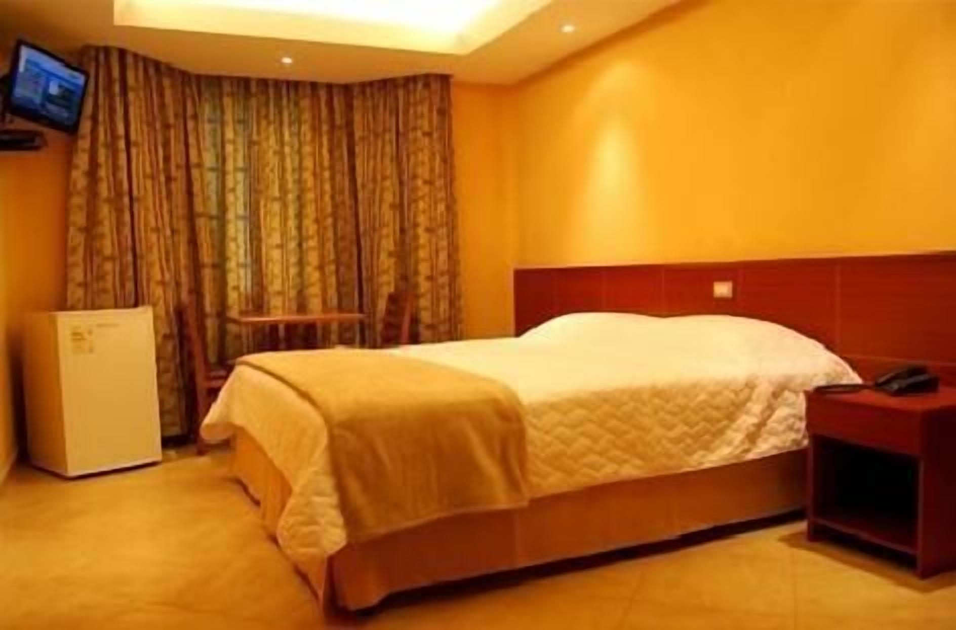 Quarto de hotel com cama, televisão na parede e uma pequena mesa.