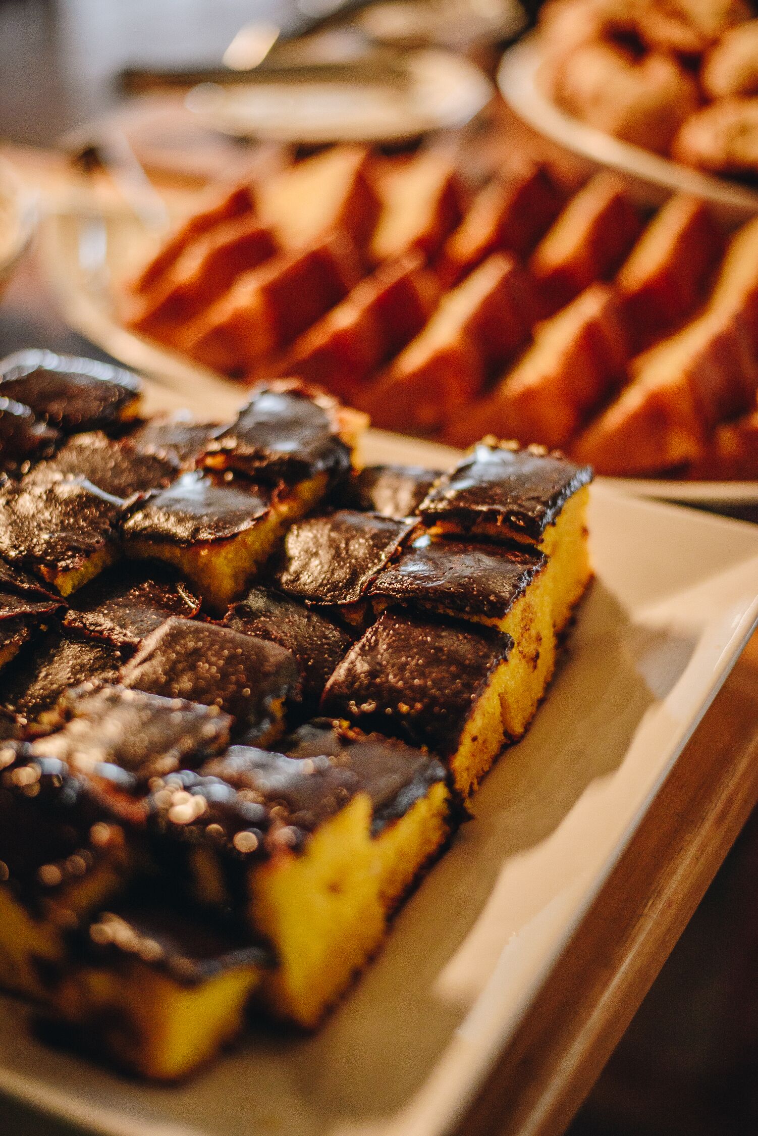 Uma bandeja de sobremesas, incluindo quadrados com cobertura de chocolate e doces redondos.