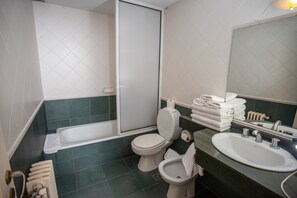 Uma combinação polibã/banheira, um secador de cabelo, sabão, champô 