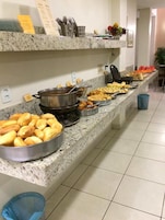 Disposição de buffet com diversos alimentos e utensílios sobre uma bancada de granito.