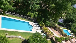 Piscina rodeada por vegetação exuberante e uma cerca de metal.