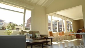 Uma sala de estar ampla, com pé direito alto, janelas grandes e um lustre moderno.