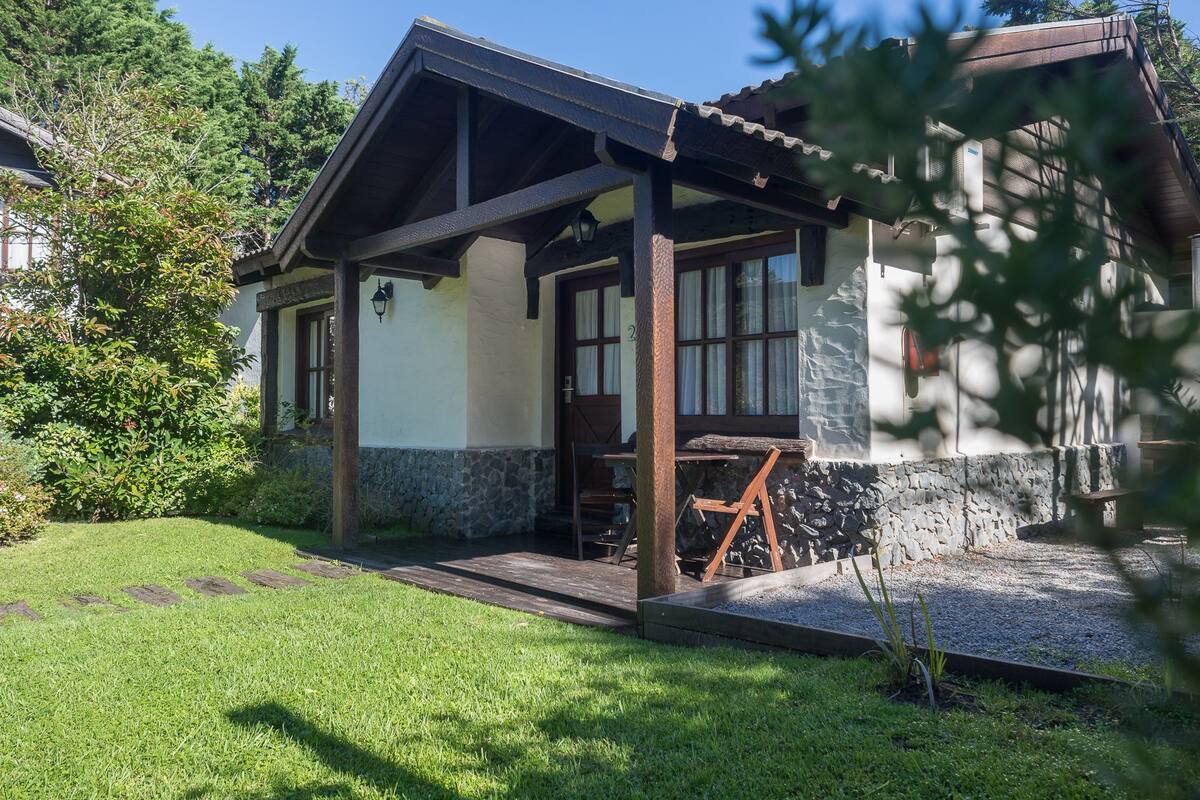 Uma casa com varanda coberta, base de pedra e um pequeno jardim.