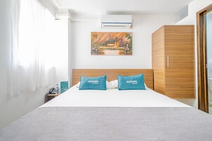 Quarto de hotel com uma cama, um quadro na parede e um guarda-roupa.