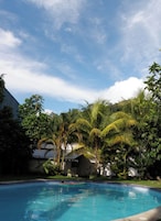 Piscina rodeada por vegetação exuberante e céu claro.
