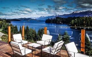 Um terraço com área de estar ao ar livre, com vista para um lago e montanhas.