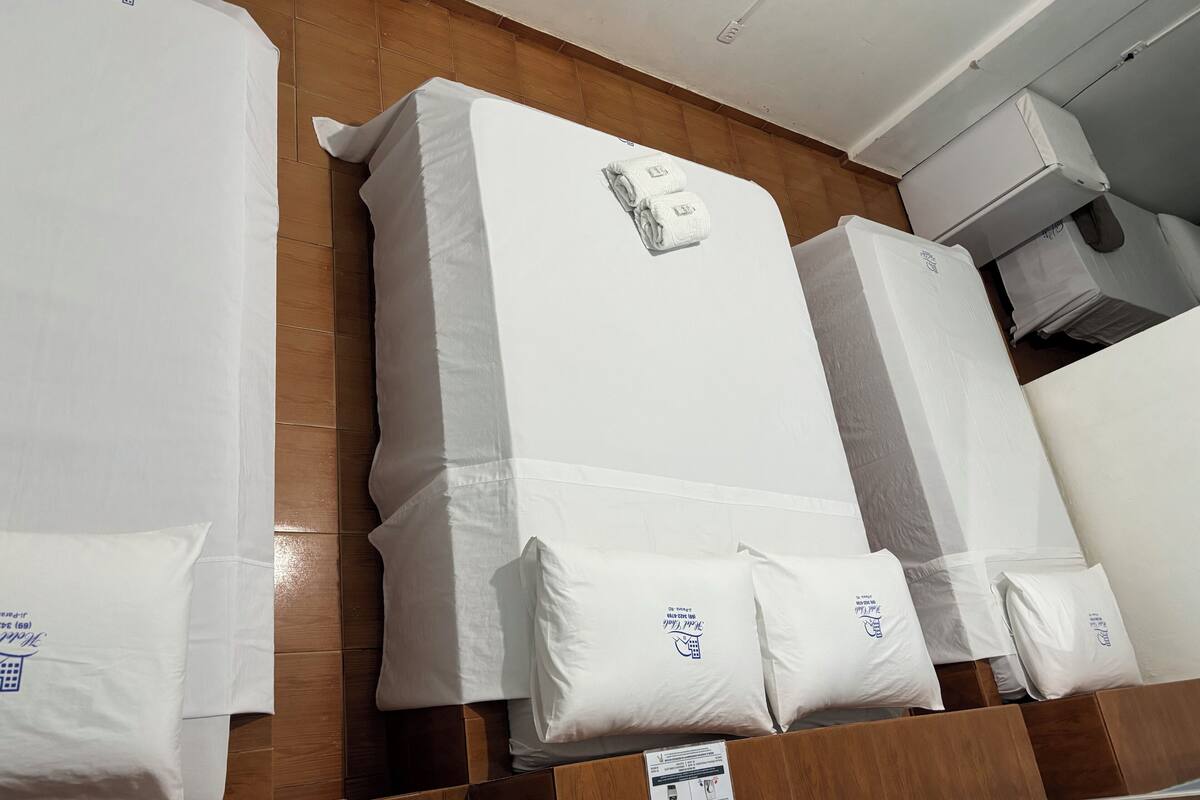 Quarto com cama grande, mesa de cabeceira e ar condicionado branco.