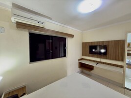 Quarto com uma janela grande, TV instalada e ar condicionado integrado.