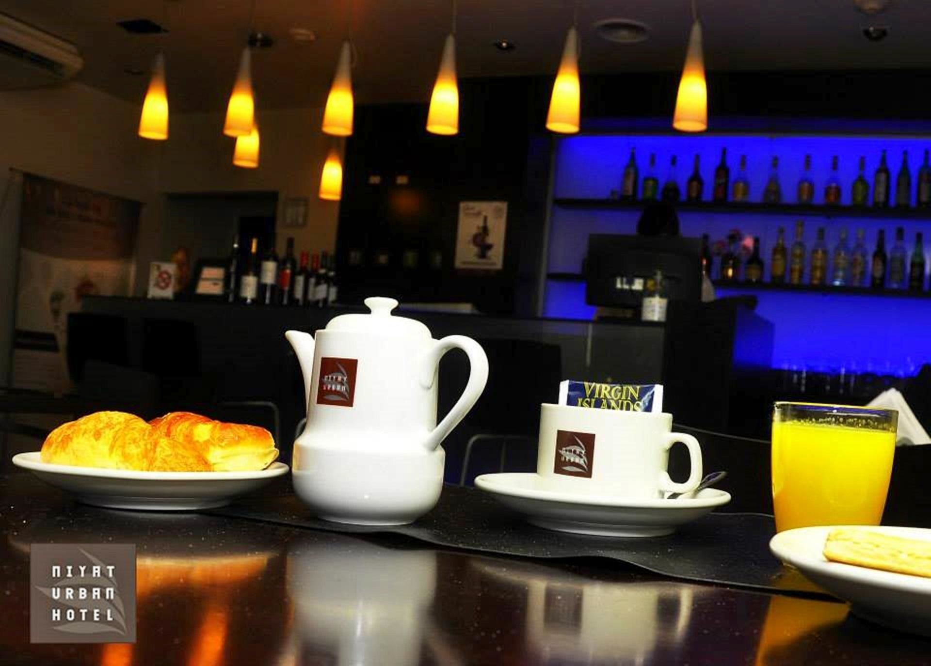 Uma mesa de pequeno-almoço com croissants, um bule de chá, uma chávena com o rótulo Ilhas Virgens e um copo de sumo de laranja numa bancada de bar.