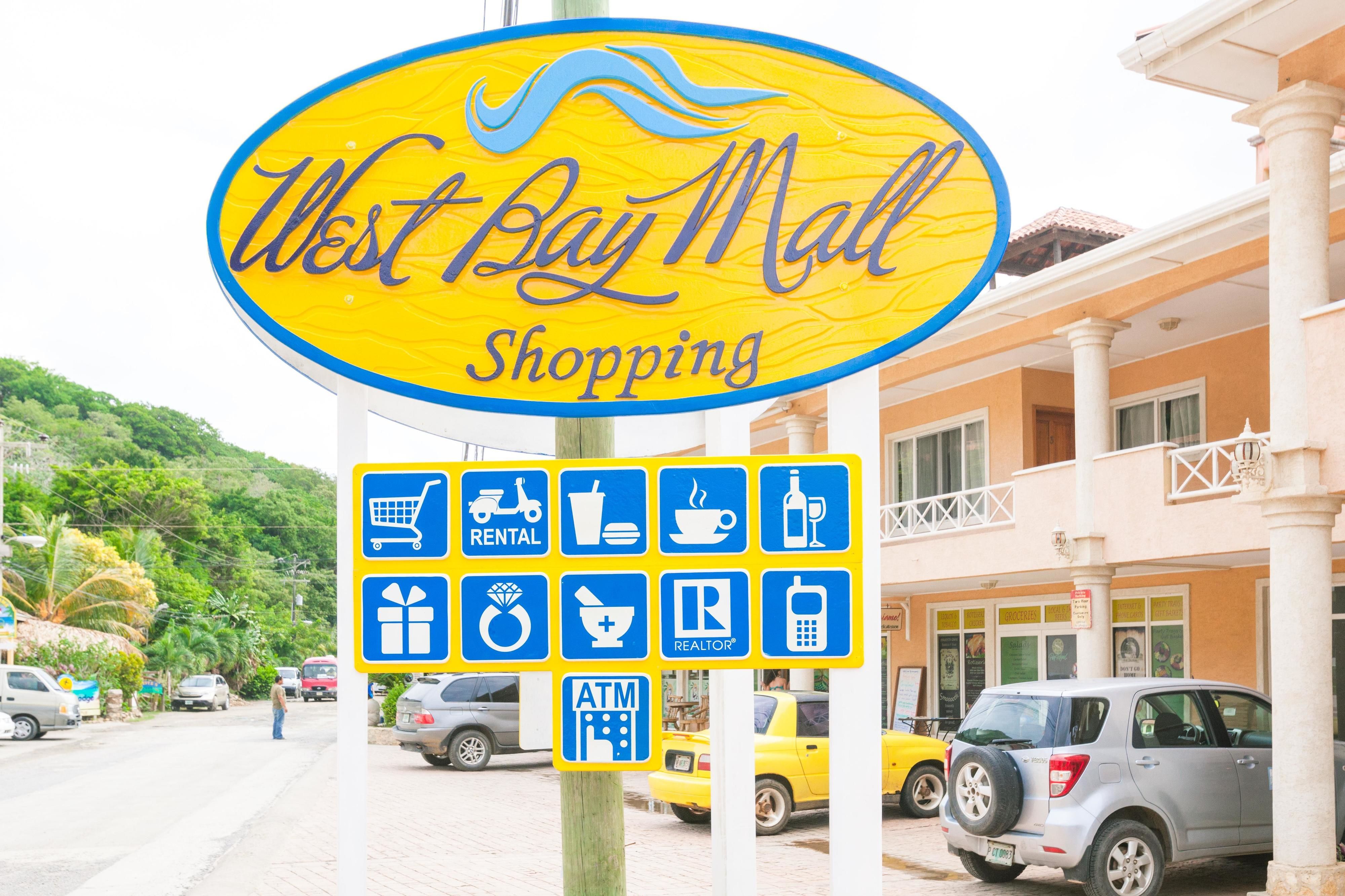 Placa para o West Bay Mall Shopping com ícones para aluguel, alimentação e serviços de caixas eletrônicos.