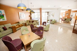 Um hall de hotel com áreas de estar, mesas e obras de arte nas paredes.