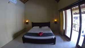 Quarto com cama, duas luminárias na parede, ventoinha no teto e janela com vista para o exterior.