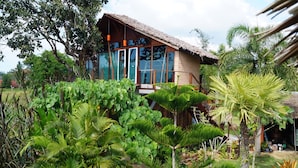 Uma casa moderna com grandes janelas de vidro, cercada por vegetação tropical exuberante.