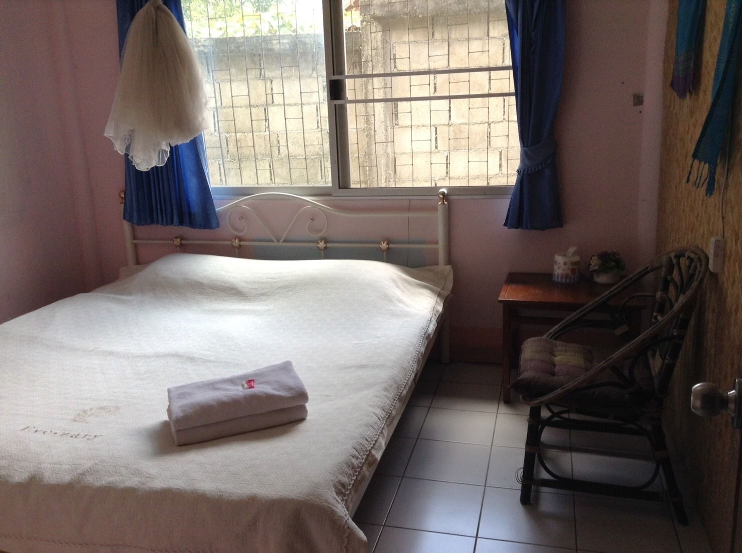 Um quarto com uma cama, uma cadeira, uma mesa pequena e uma janela com cortinas.