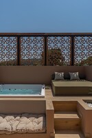 Terraço no telhado com hidromassagem, área de estar acolchoada e deck de madeira.