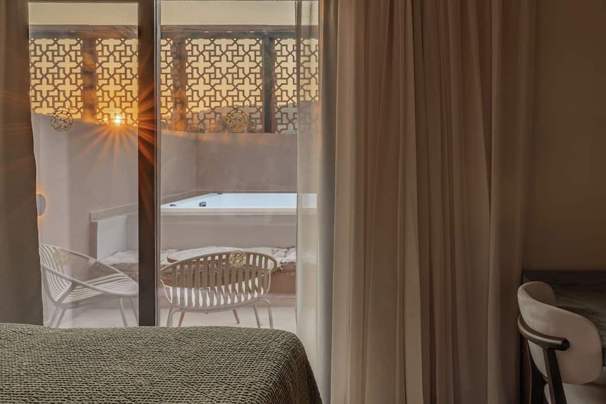 Quarto de hotel com cama, mesa de trabalho e varanda com vista.