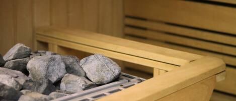 Uma sauna de madeira com um banco e uma bacia de pedra.