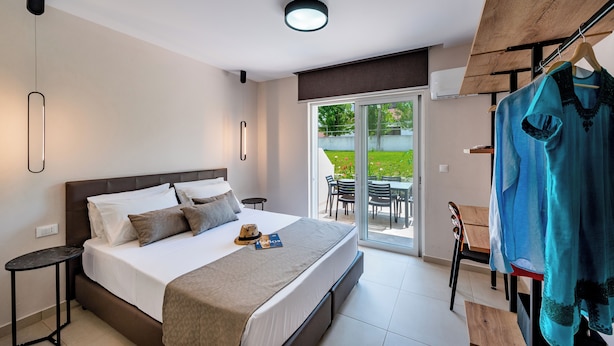 Quarto moderno com uma cama grande, uma mesinha e vista para o exterior através de uma porta de correr de vidro.