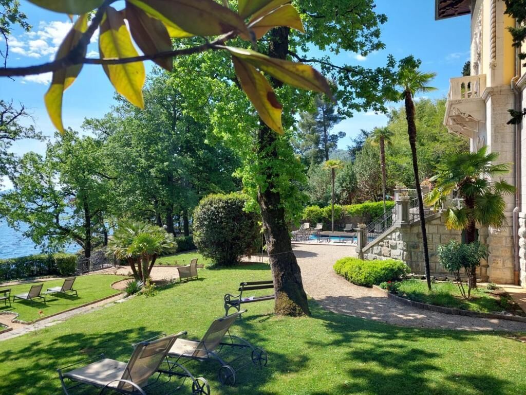 Um jardim bem cuidado com piscina, espreguiçadeiras e um edifício de pedra.