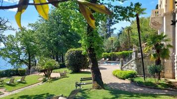 Um jardim bem cuidado com piscina, espreguiçadeiras e um edifício de pedra.