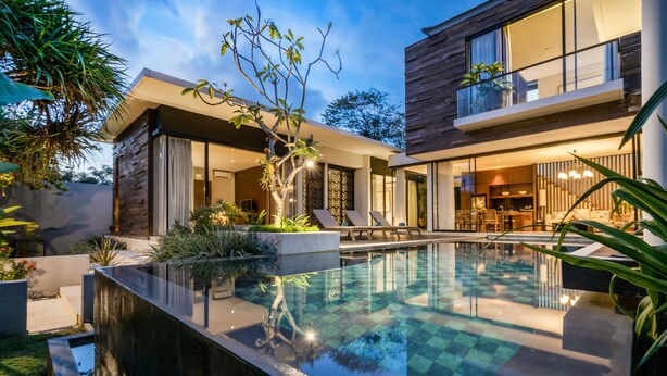Uma casa moderna com piscina, janelas amplas e área de estar externa.