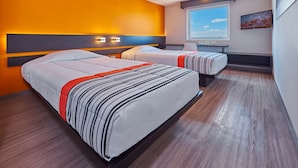 Quarto de hotel com duas camas, uma janela grande e vista do céu.